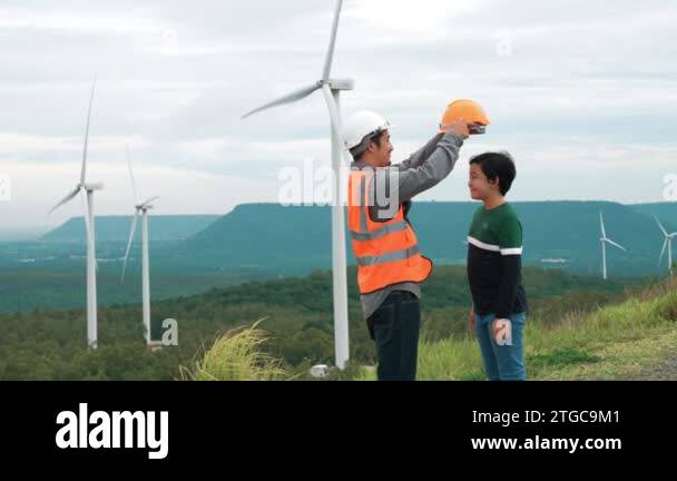 Engineer with his son on a wind farm atop a hill or mountain in the ...