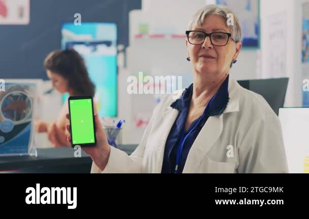 Elderly specialist holding greenscreen display on smartphone, using ...
