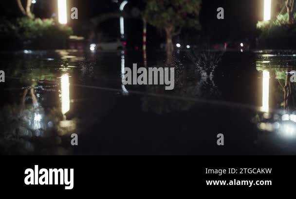 Close-up at night, drops of summer or autumn rain fall on the asphalt ...