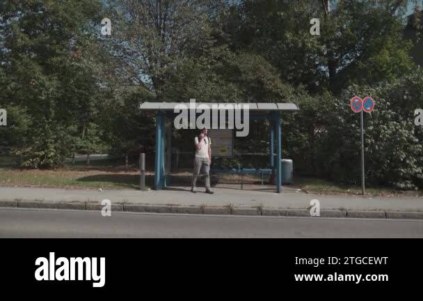 Frustrated man waits for bus that is delayed at halt and calls on his ...