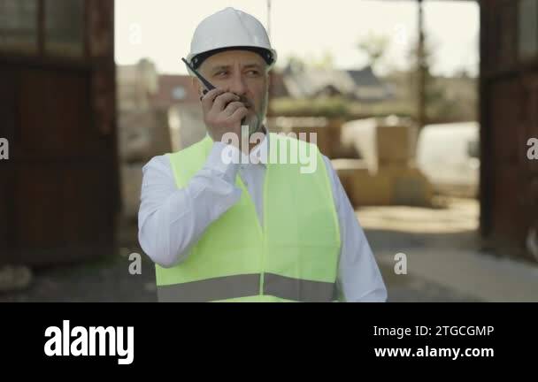 Male inspector in white hard hat and reflective vest giving ...