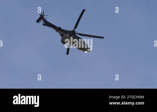 Military helicopter in flight at high speed in a narrow mountain valley ...