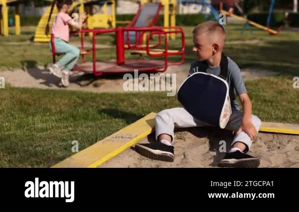 crying child with broken limb arm sits outdoors and looking how kid ...