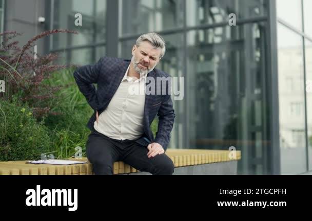 Tired entrepreneur businessman having severe back pain ache sitting on ...