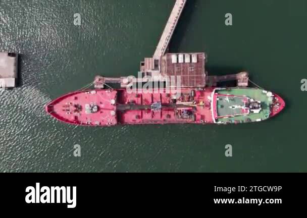 Red tanker ship loading and unloading oil and gas storage at industrial ...