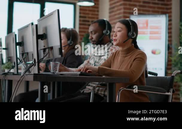 Young woman working at customer assistance service, using microphone on headphones. Female ...
