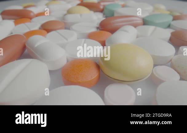 Medical tablets, pills and capsules rotating close up. White, blue and ...