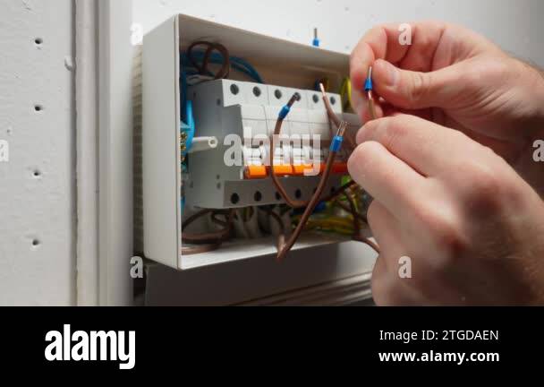 An electrician putting blue bushing ferrules on wires and clamping them ...