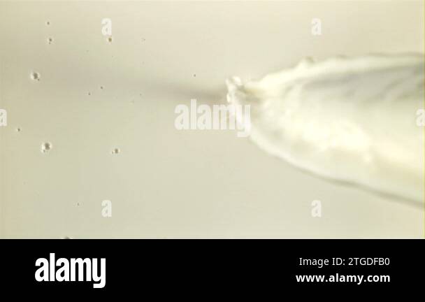 A stream of milk flows with air bubbles. Top view. On a white ...