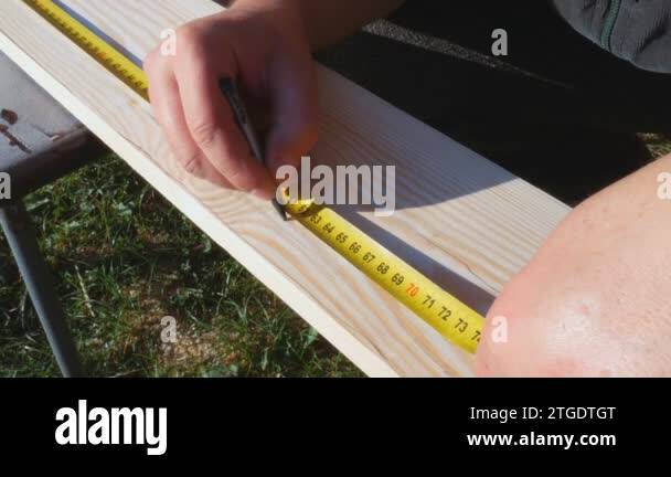 Using a ruler, the worker marks the dimensions with a pencil. Yellow ...