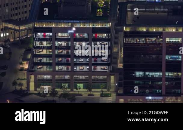 Office buildings with glowing panoramic windows at night aerial timelapse. Glowing lights in ...