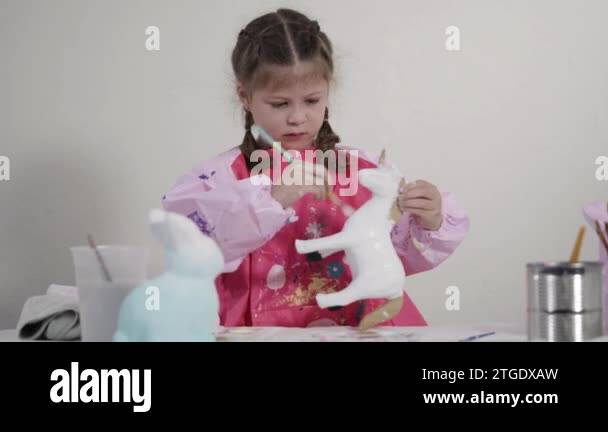 Little girl painting paper mache figurine at homeschooling art class ...