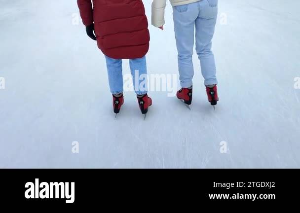 Two people skating on public open-air ice skating rink in city on ...