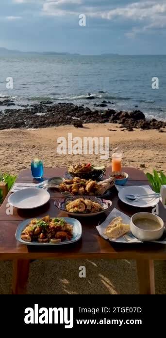 Dinner table with Thai food and bbq fish on the beach of Pattaya ...