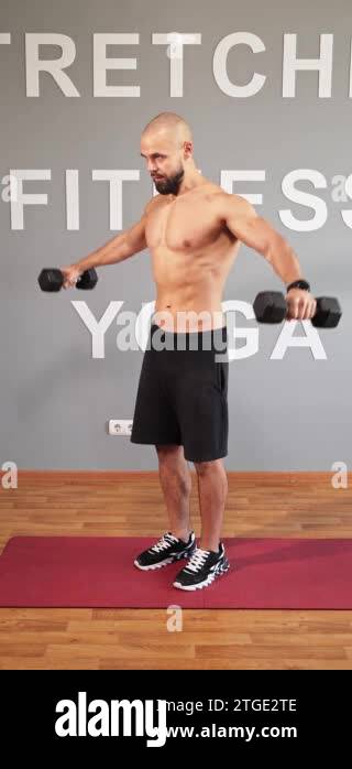 Sportsman in the gym shakes the muscles of the arms, exercises with a ...