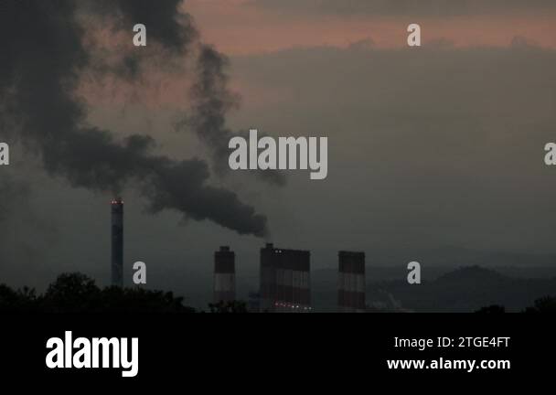 Coal power plant with steam pouring out of stacks at dusk. Industrial smoke stack of coal power ...
