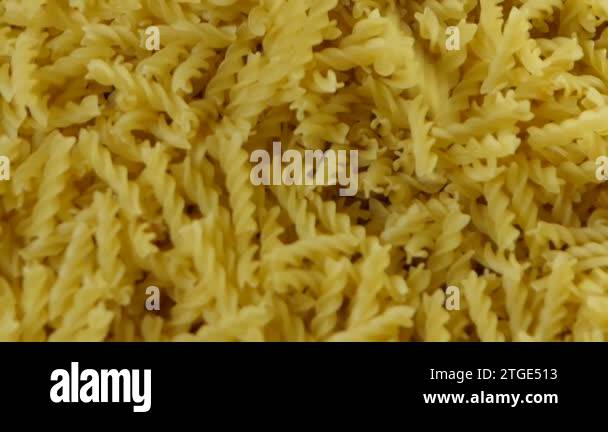 Spiral pasta spilling over a pile of dry macaroni. Production of ...