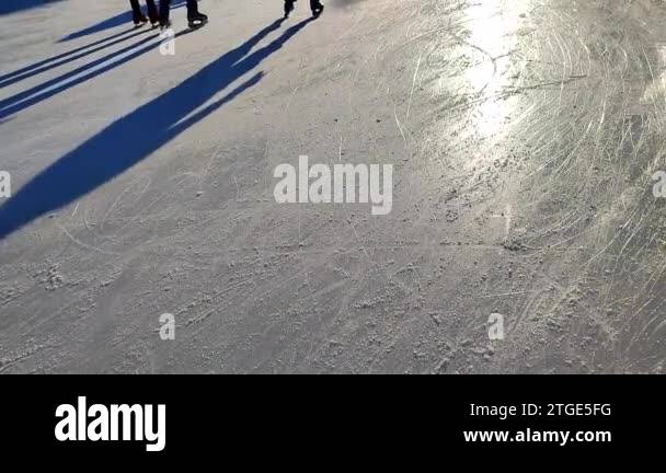 Two people skating on public open-air ice skating rink in city on sunny ...