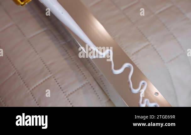 Zig zag white glue applying on metal profile surface, workman using ...