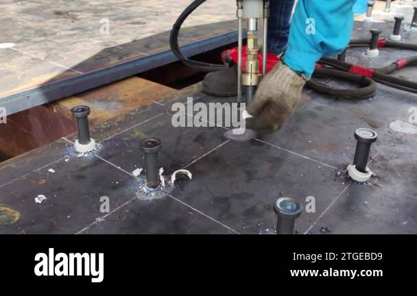 Welder is using a Stud Welding Machine to weld stud bolt-on steel ...