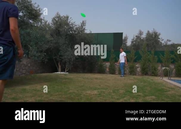 Man tries to catch frisbee launched by friend in yard near swimming ...
