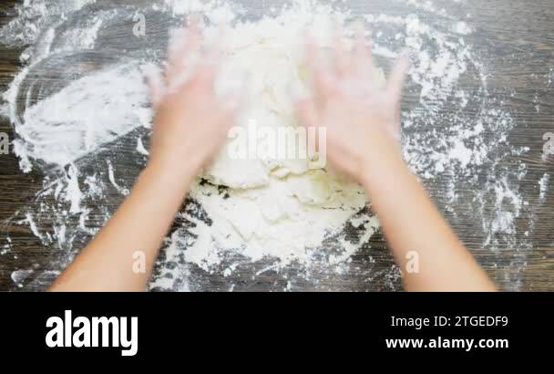Female hands kneading dough in flour on the table. Close up view of ...