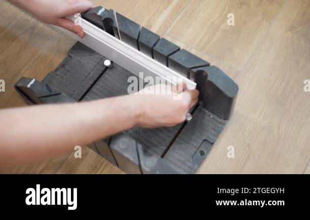 Workman measuring and fixing white plastic plinth for cutting and ...