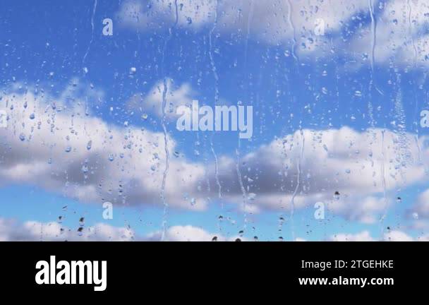 Rain Drops Flow Down Glass Against a Background of Moving Clouds and ...