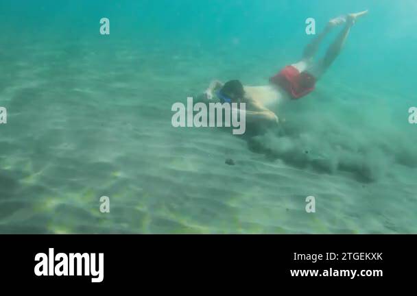 A young guy swims underwater in the Mediterranean Sea without special ...