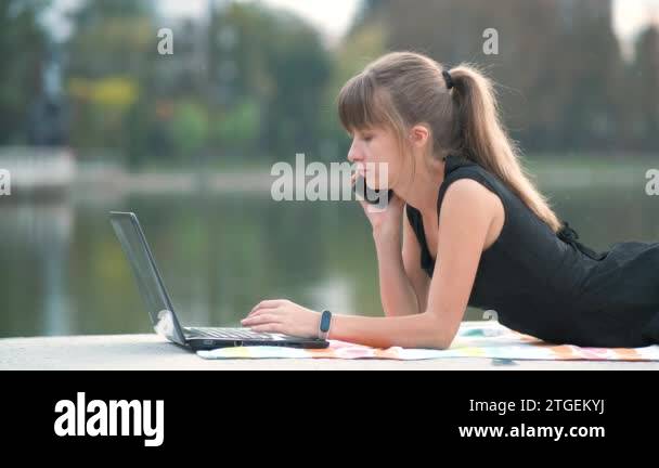 Angry woman talking angrily on mobile phone while working behind laptop ...