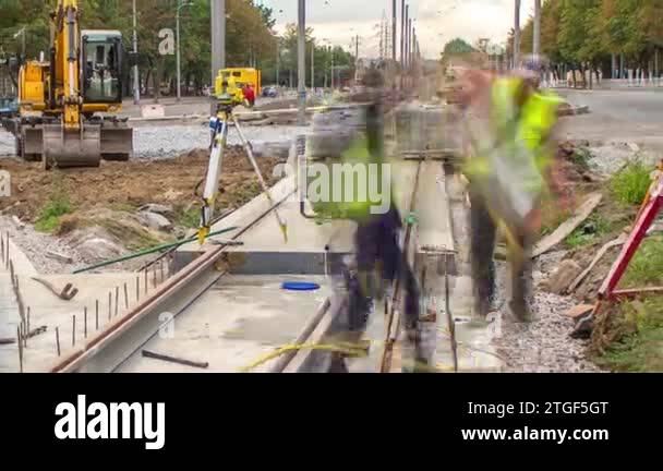 Workers drill holes for mounting and install new tram rails on concrete ...