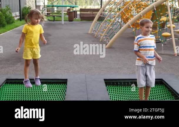 Little happy children jump on a street trampoline in summer in a modern ...