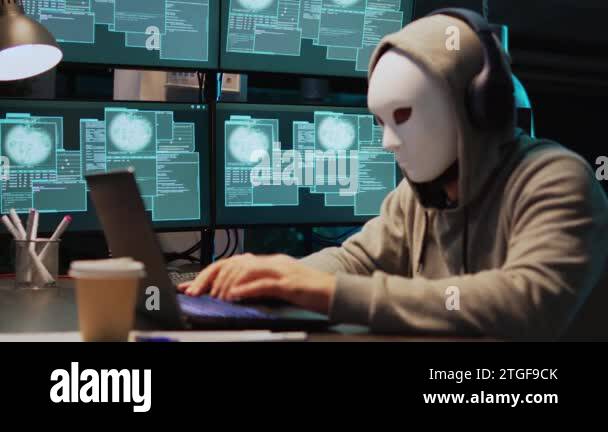 Masked cyber thief hacking computer network at night, working on laptop ... Masked cyber thief hacking computer network at night, working on laptop ...