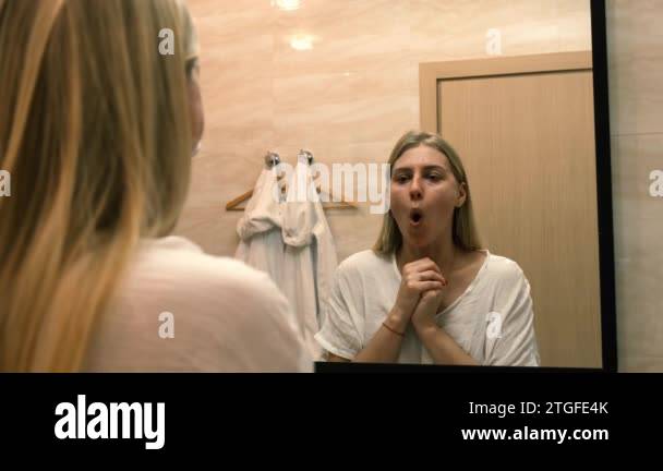 Aging. Loose skin. Young woman doing facelift exercises while looking ...