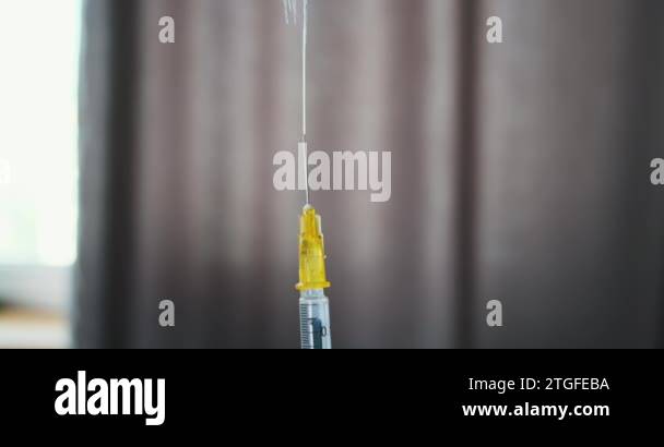Thin insulin syringe, liquid comes out of needle, medicine. Drop falls ...