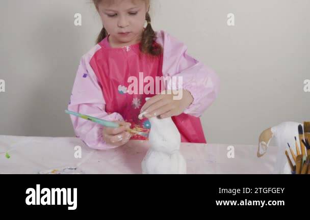 Little girl painting paper mache figurine at homeschooling art class ...