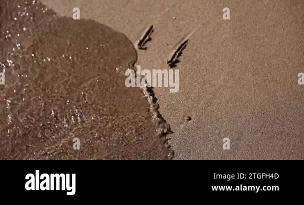 Sad emoticon drawn on sand washes away with wave. Concept of depression ...