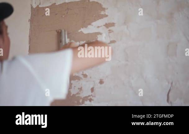 Professional plasterer female spackles a wall, applies and spreads ...