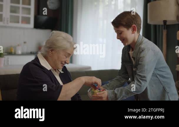 Boy offering candy in bowl to his elderly grandmother.Little boy ...