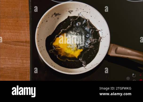 burnt egg on a white pan on a black stove. fried eggs in black oil ...