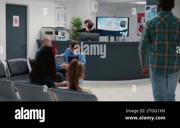 Busy hospital reception waiting area with patients in row to start ...