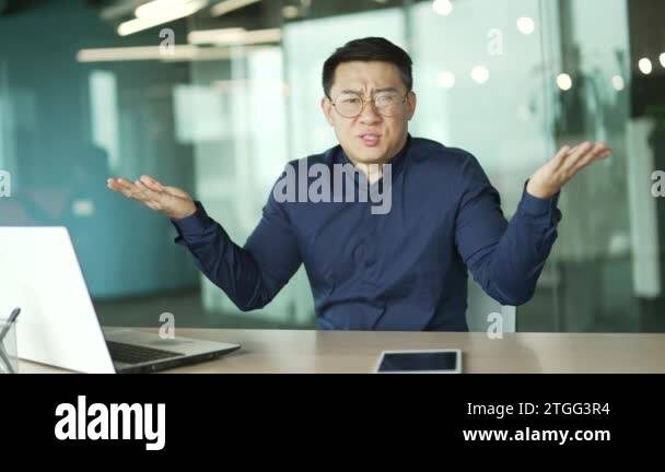 Puzzled asian businessman employee sitting next to laptop computer and ...