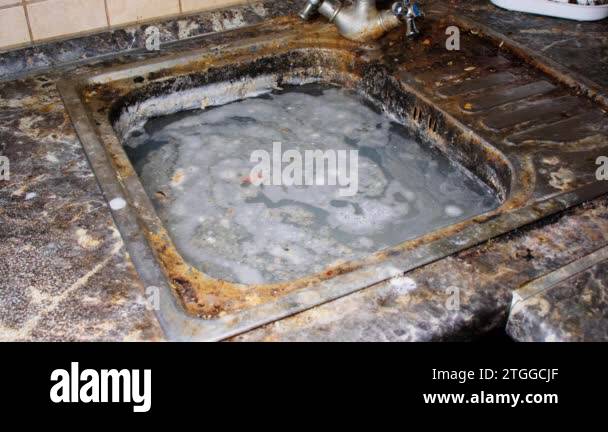 Very dirty sink. The kitchen sink is filled with soapy water, filled ...