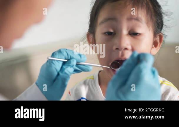 Dental kid health examination. Doctor examines oral cavity of little child uses mouth mirror to ...