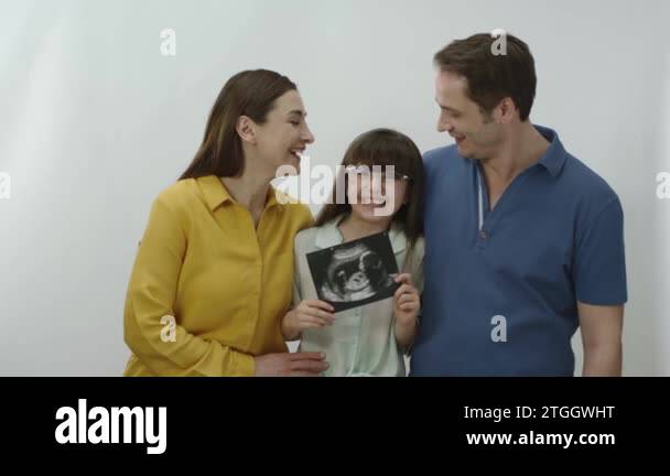 Young parents and their daughters look at ultrasound film approaching ...