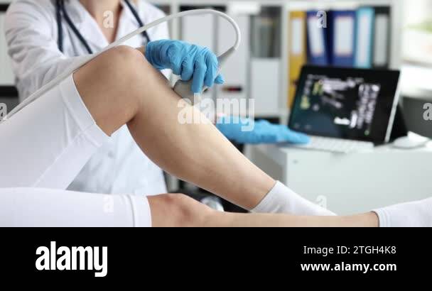 Doctor conducts ultrasound examination of knee joint in clinic closeup ...
