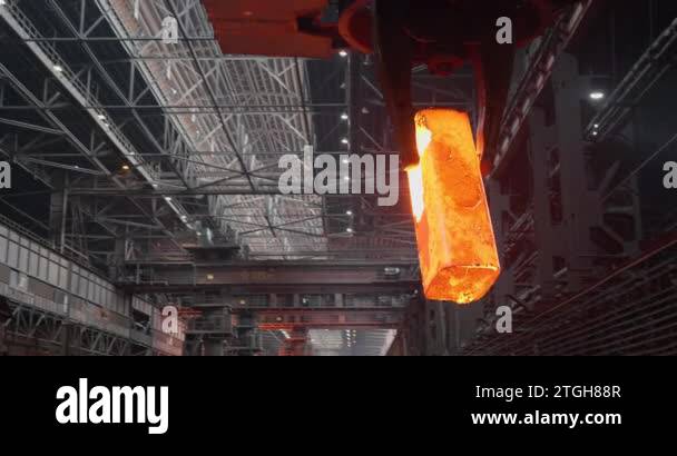 The crane gives out a mold of molten steel and puts it on a trolley for ...