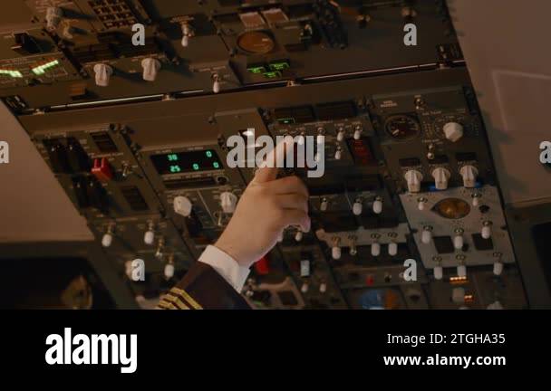 Male captain pushing dashboard buttons to start airplane engine, using control panel command to ...