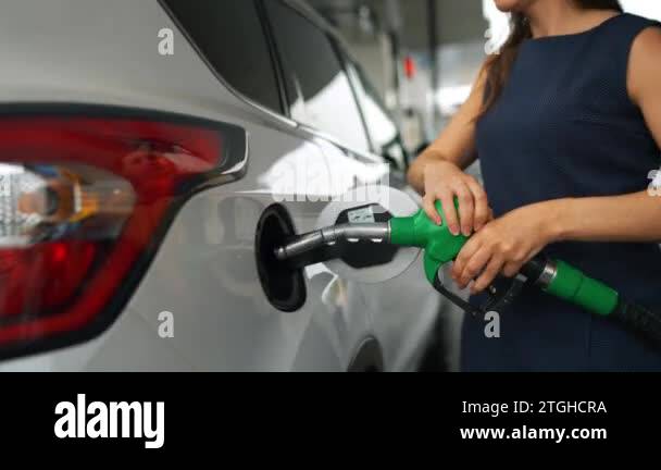 Woman inserts a fuel gun in a gas tank to refuel a car. Concept of ...