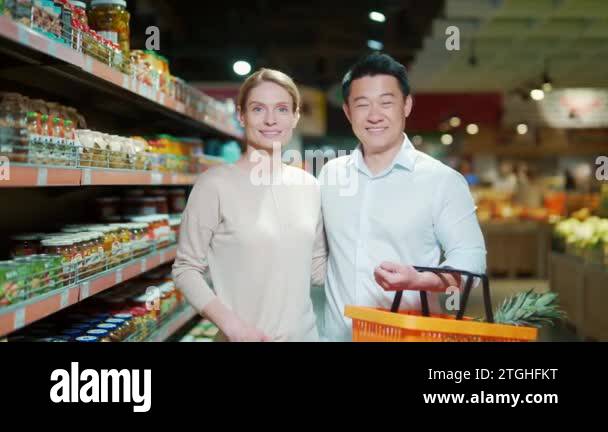 Portrait of a happy asian couple of consumers, supermarket shoppers or ...